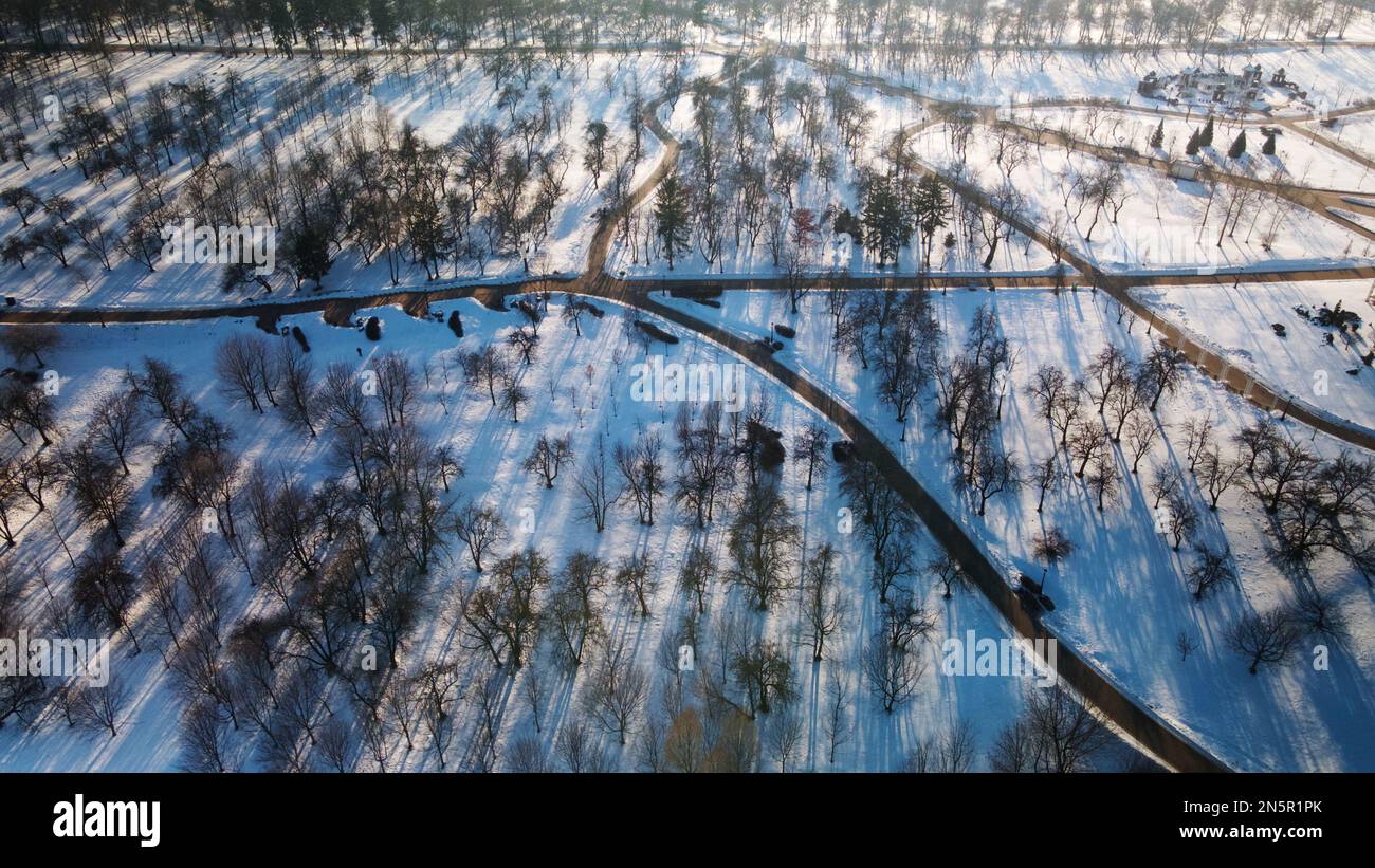 A winding bike path in a city park. City park in winter. Snow lies on ...