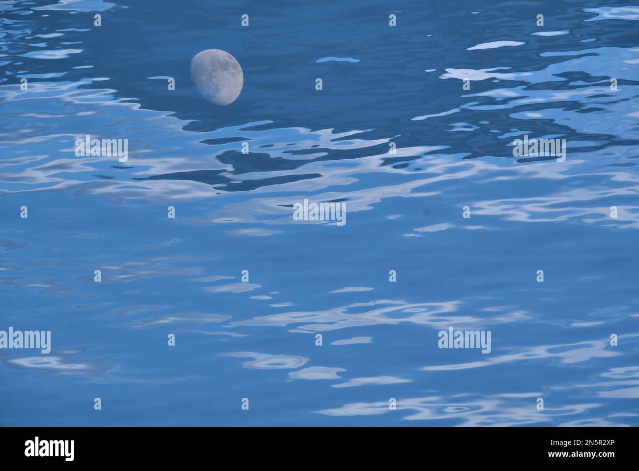 Double exposure of bright moon over dark, rippled water Stock Photo - Alamy