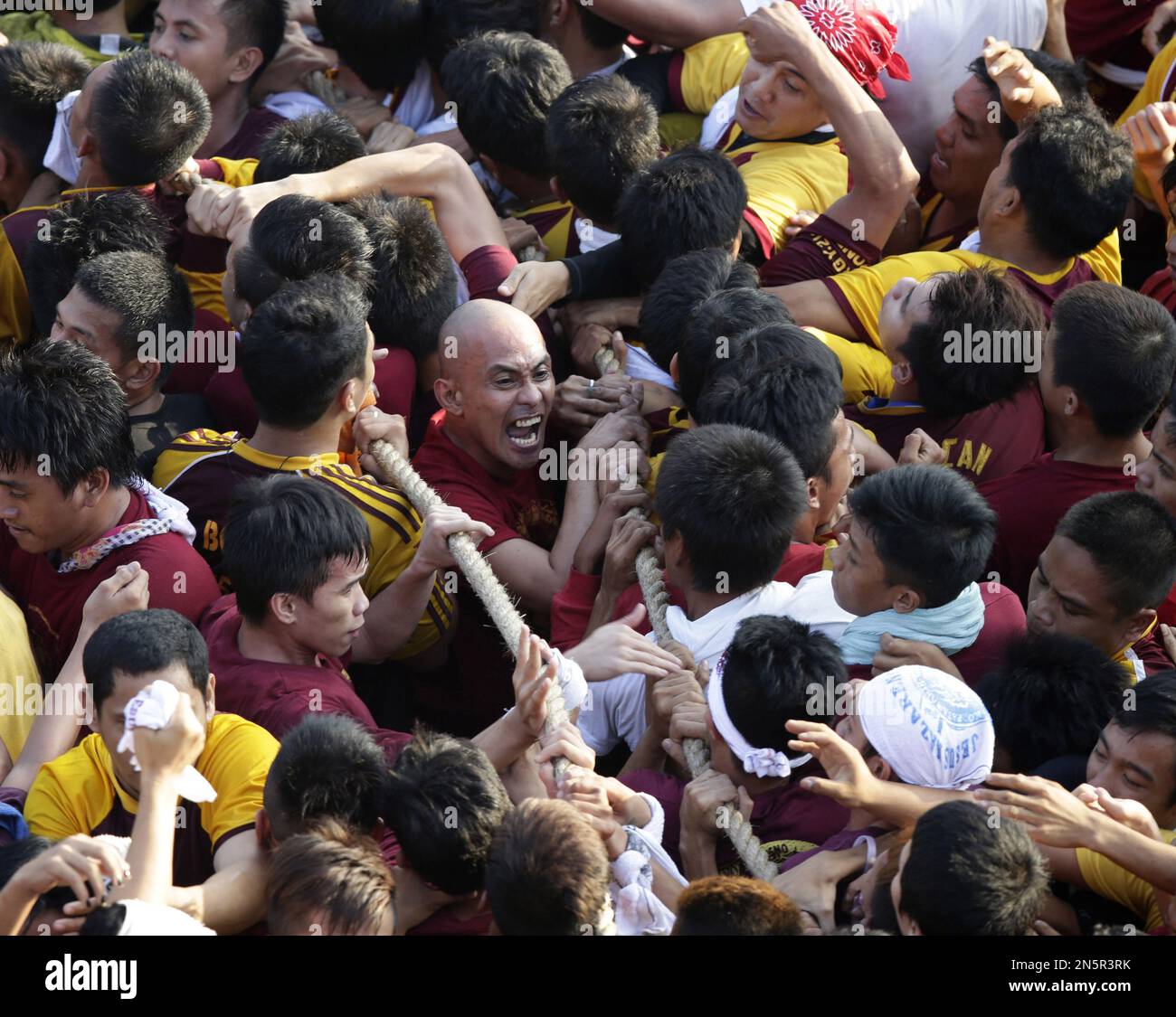 Filipino Catholic devotees grab the rope that is tied to the carriage ...