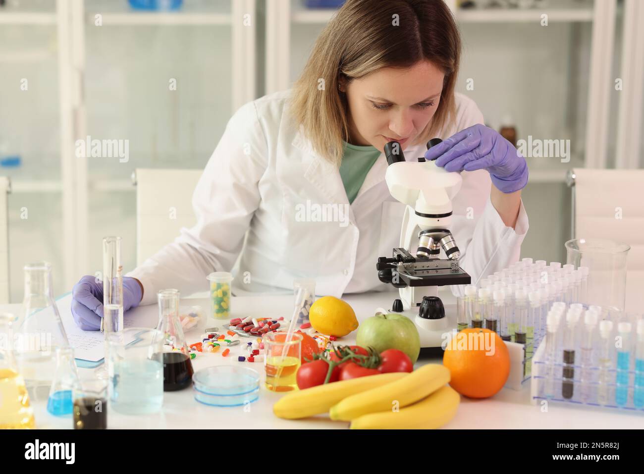Female scientist with microscope, test tubes, laboratory glassware and ...