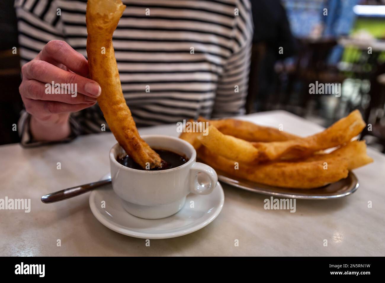 Churros being dipped into chocolate Stock Photo - Alamy