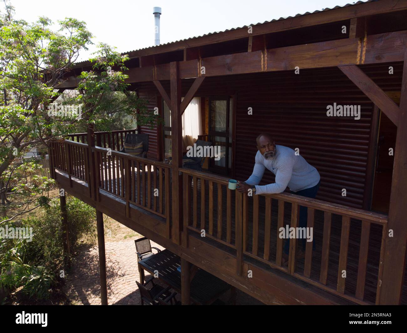 African american man standing in veranda of log cabin Stock Photo - Alamy