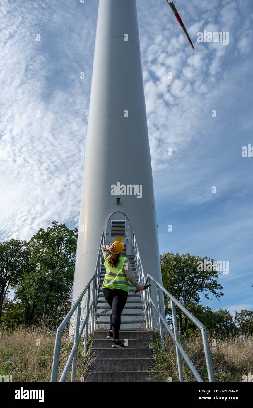 Female engineer with brown curly hair and yellow helmet is walking up ...