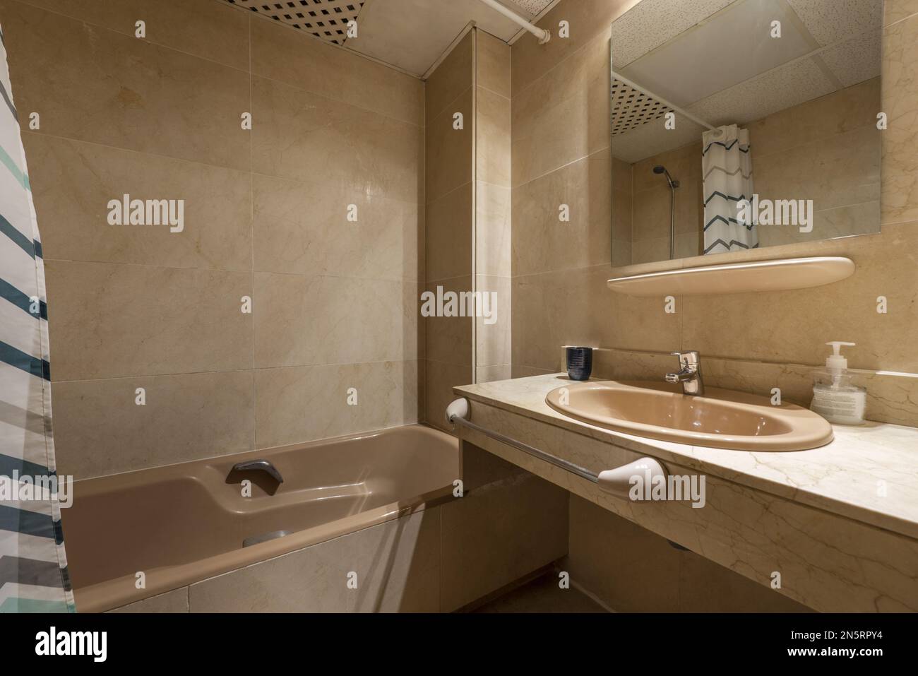 Conventional bathroom with marble countertop, brown porcelain bathtub ...