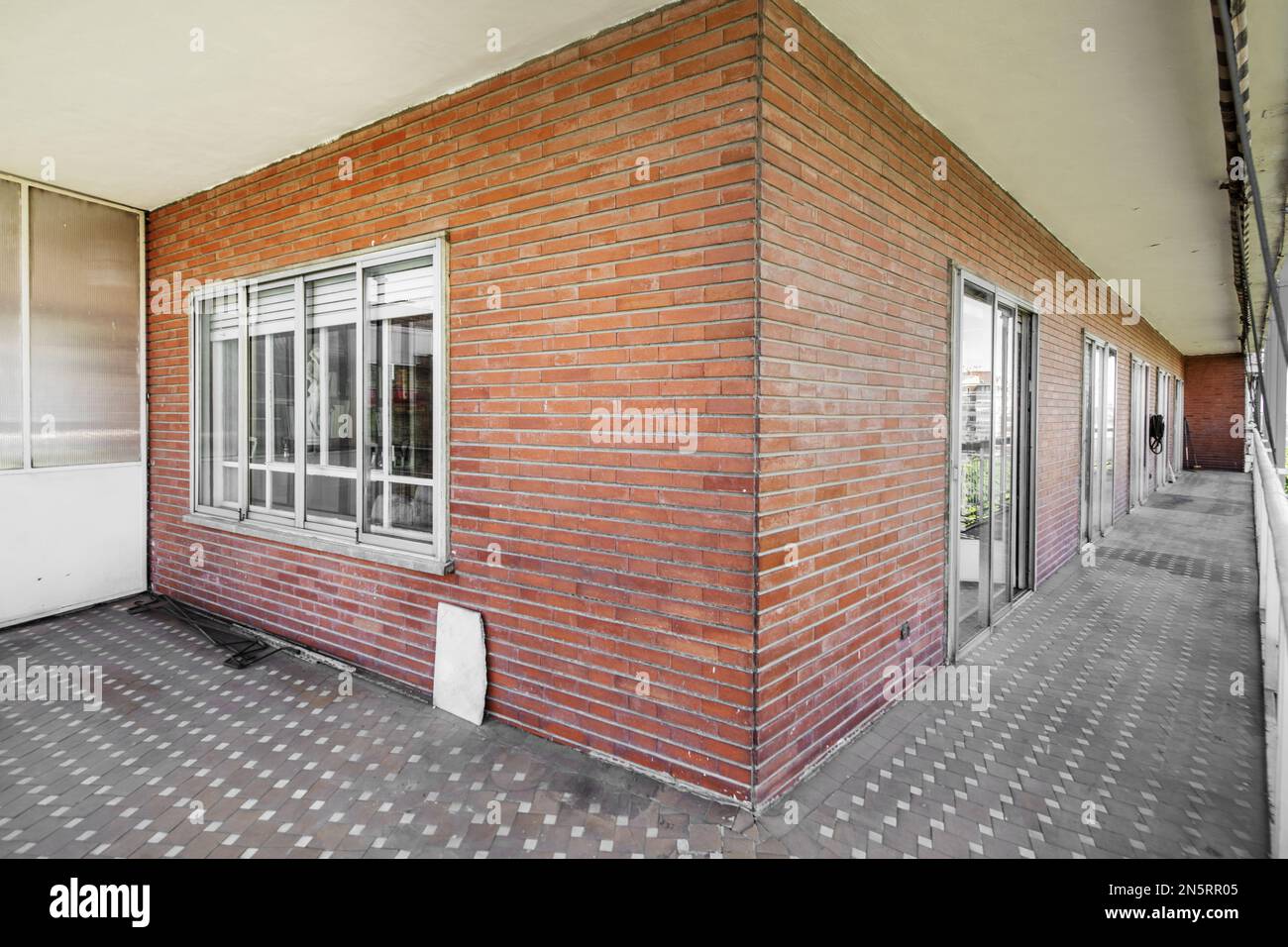 Terrace porch of a house with brick walls and several sliding doors to ...