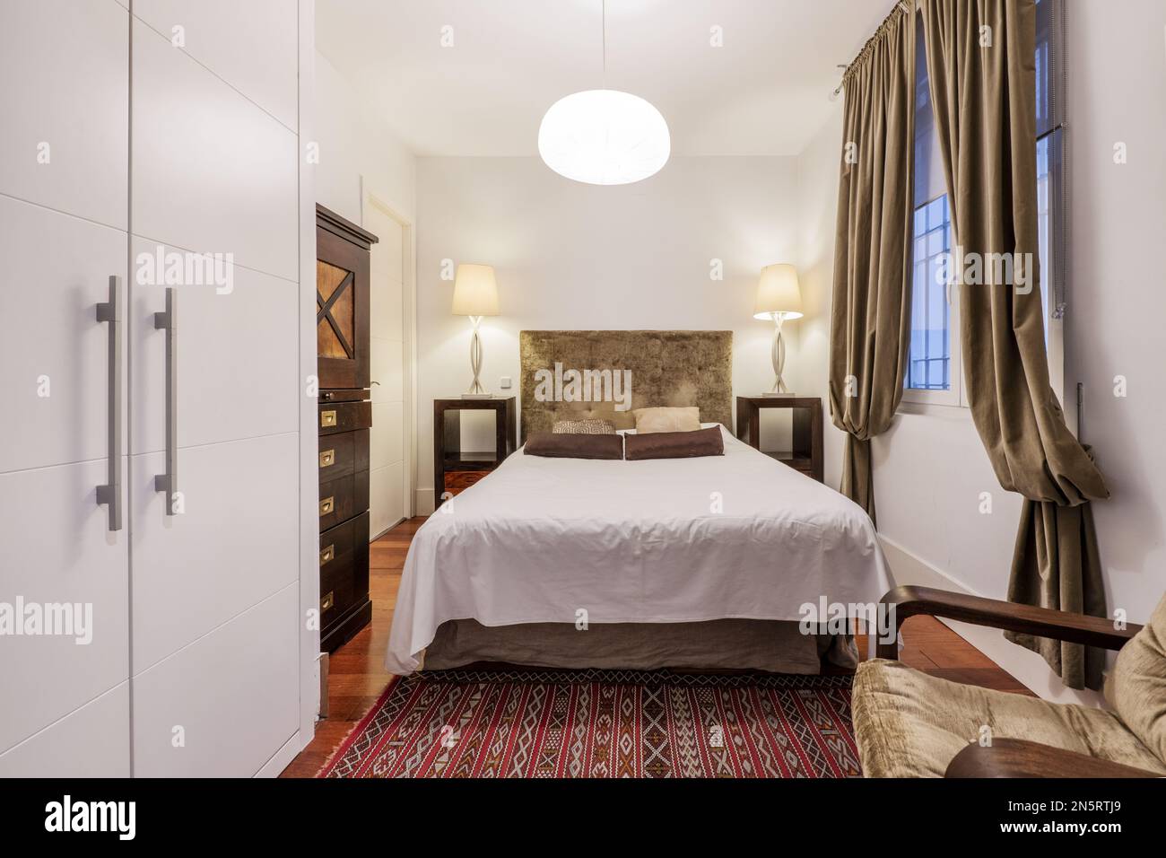 Regal style bedroom with white wardrobe, red rug, dresser with dark ...