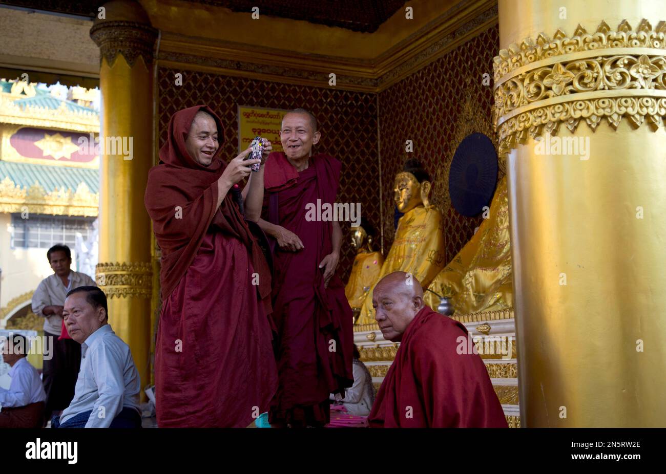 A Buddhist monk meditates as anothers laugh after taking a picture of ...