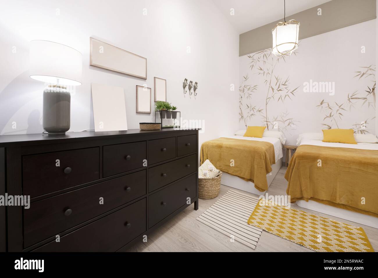 Bedroom with single beds separated by a wooden stool with mustard ...