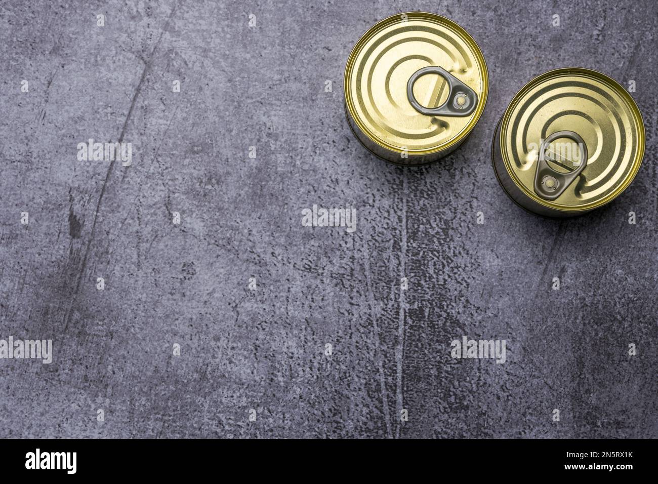 Two small circular tin cans closed with easy-open rings on gray surface ...