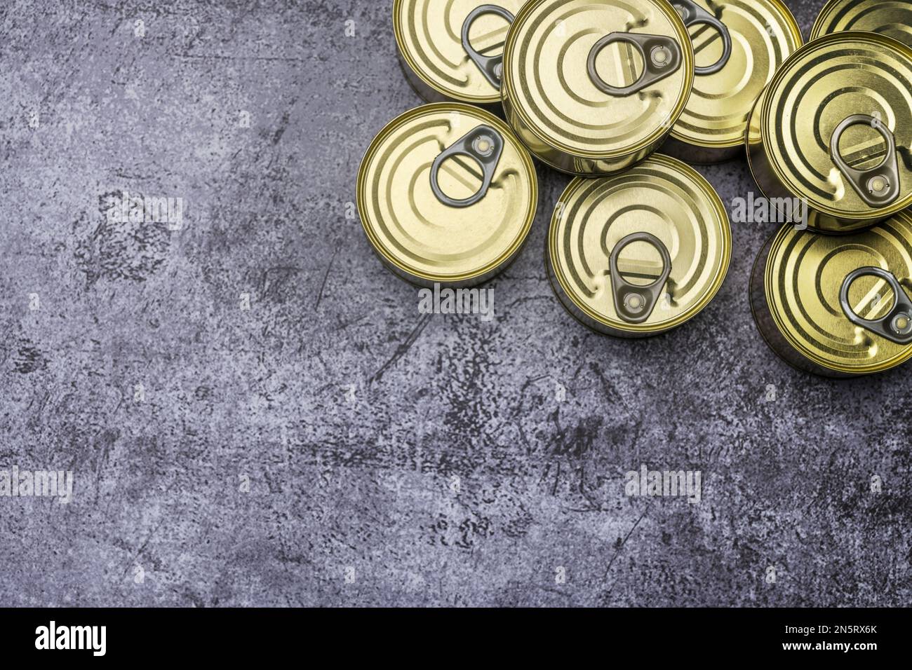 A group of small circular cans closed with easy-open rings on gray ...