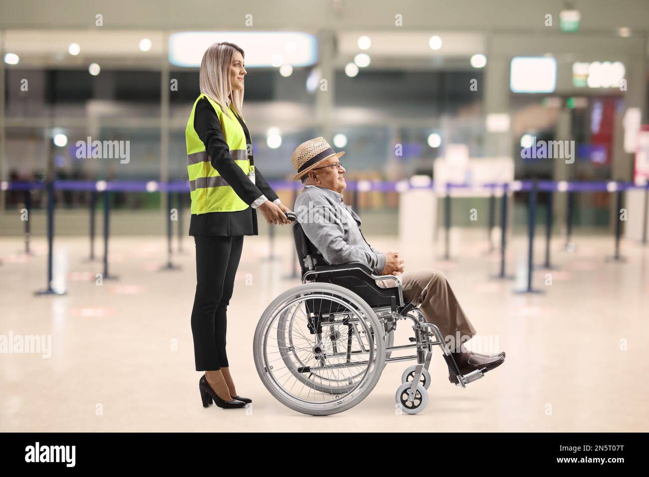 Female assitance worker at the airport standing with an older passenger ...