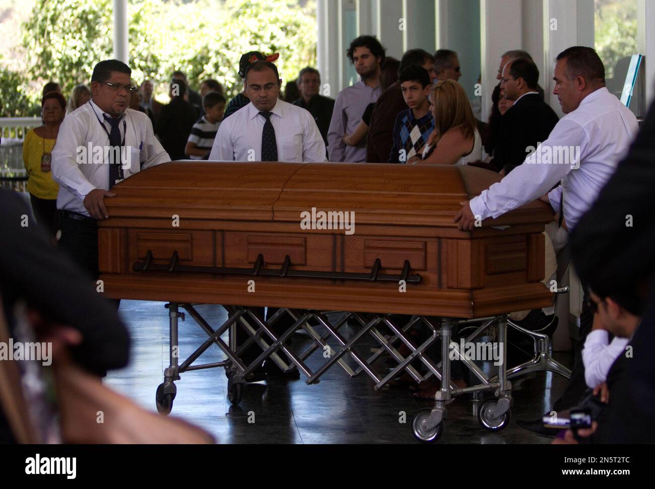 Funeral service workers push the coffin that contain the remains of ...