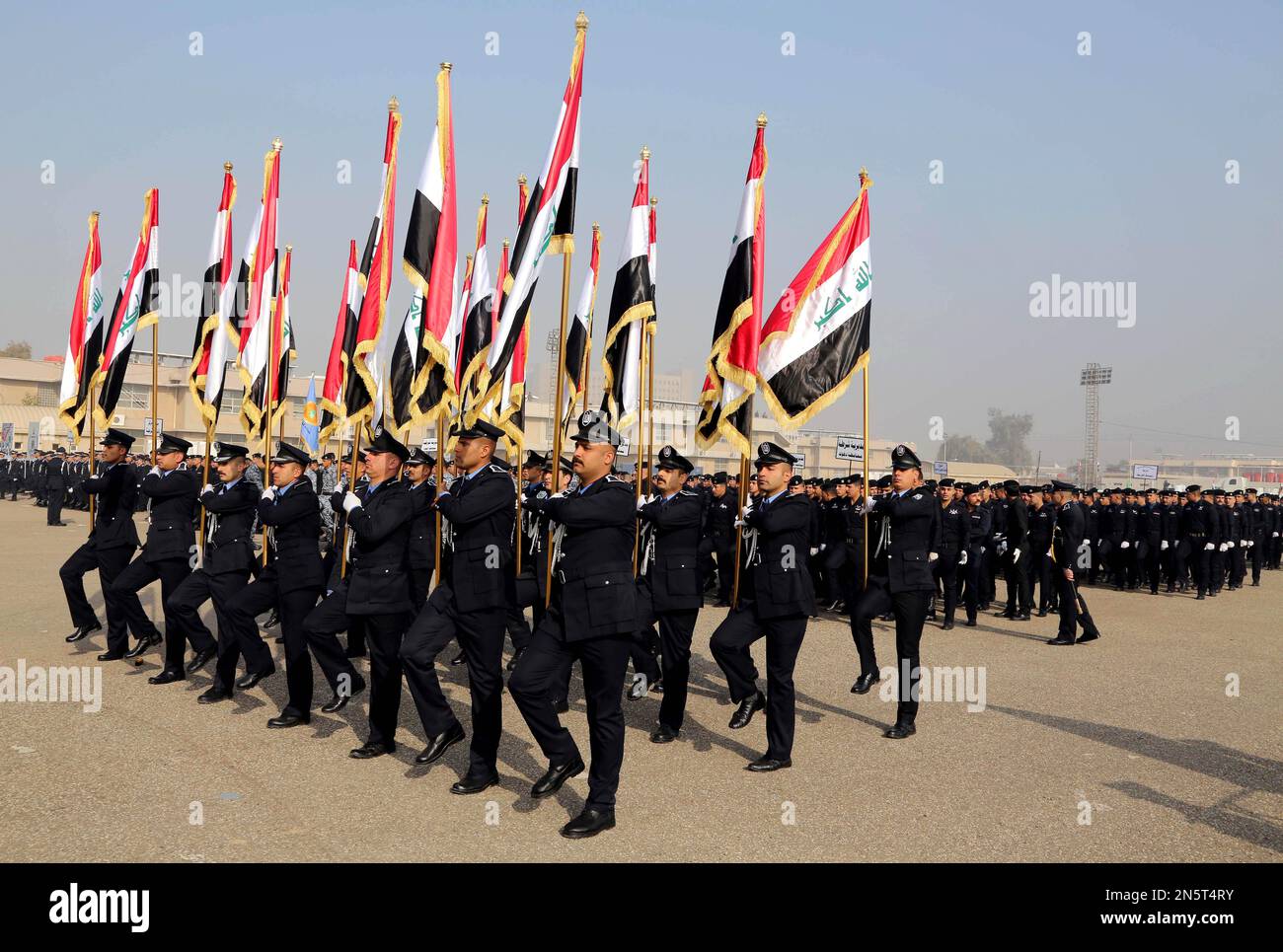 Iraqi policemen march holding national flags during a ceremony marking ...