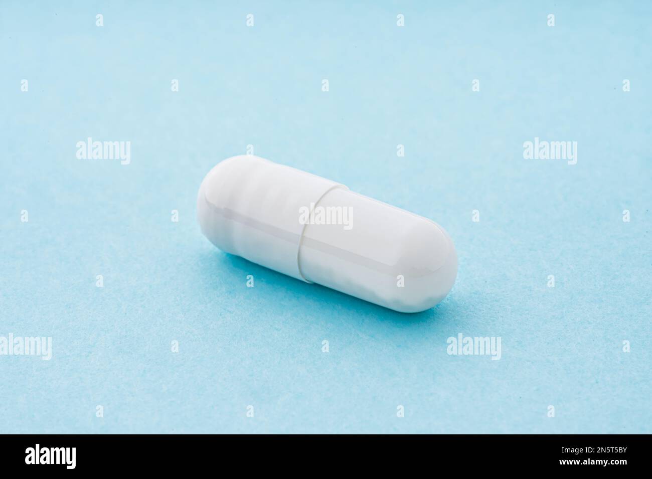 Gel capsule. White medicine capsule on light blue background. food ...