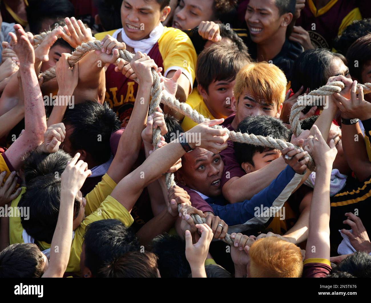 Filipino Catholic devotees grab the rope which is tied to the carriage ...