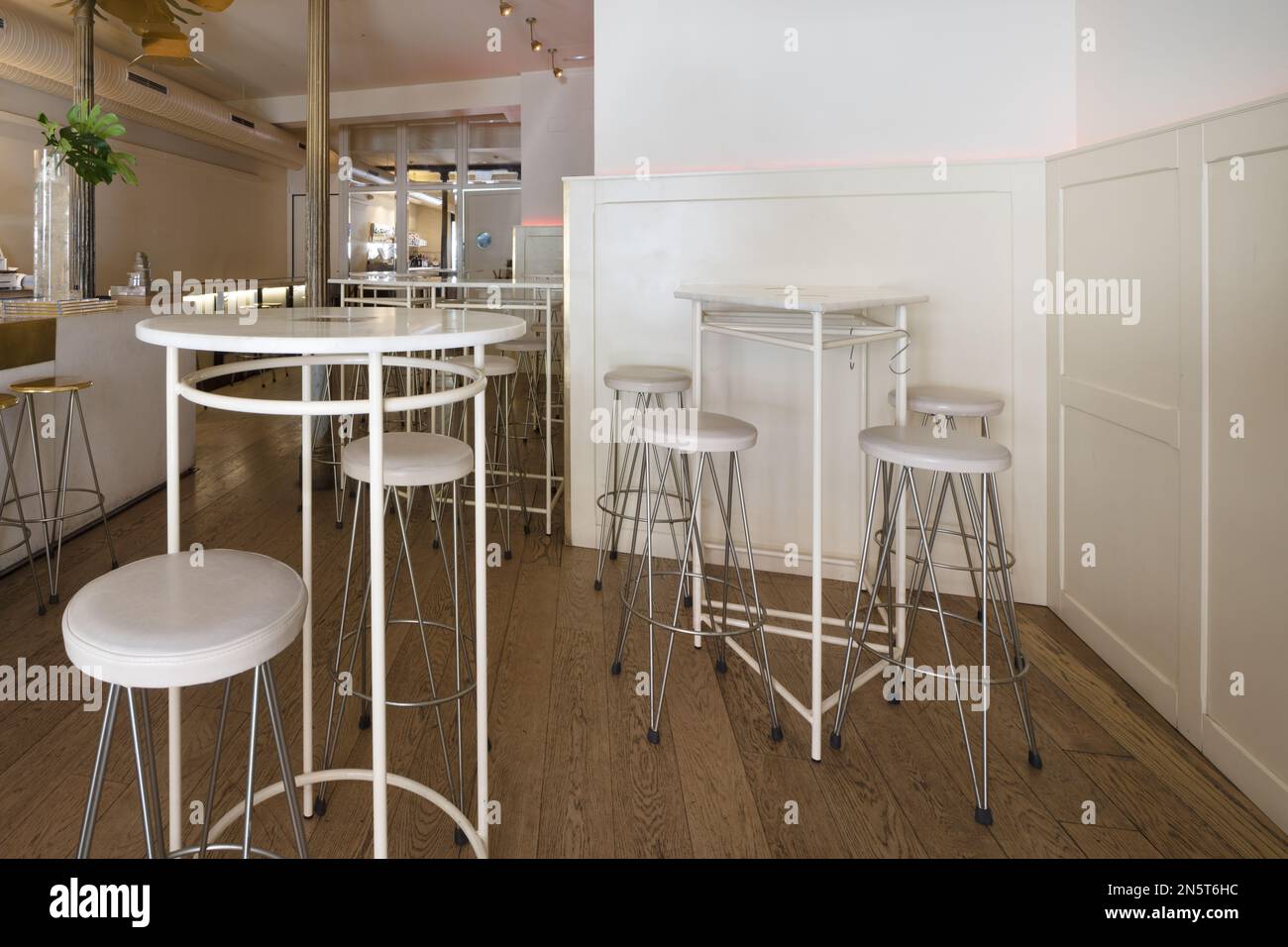 Circular high tables with matching white upholstered stools in a ...