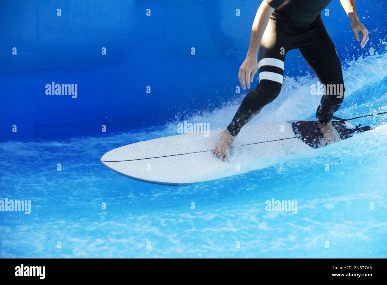 A surfer in a wetsuit riding the waves in a swimming pool Stock Photo ...