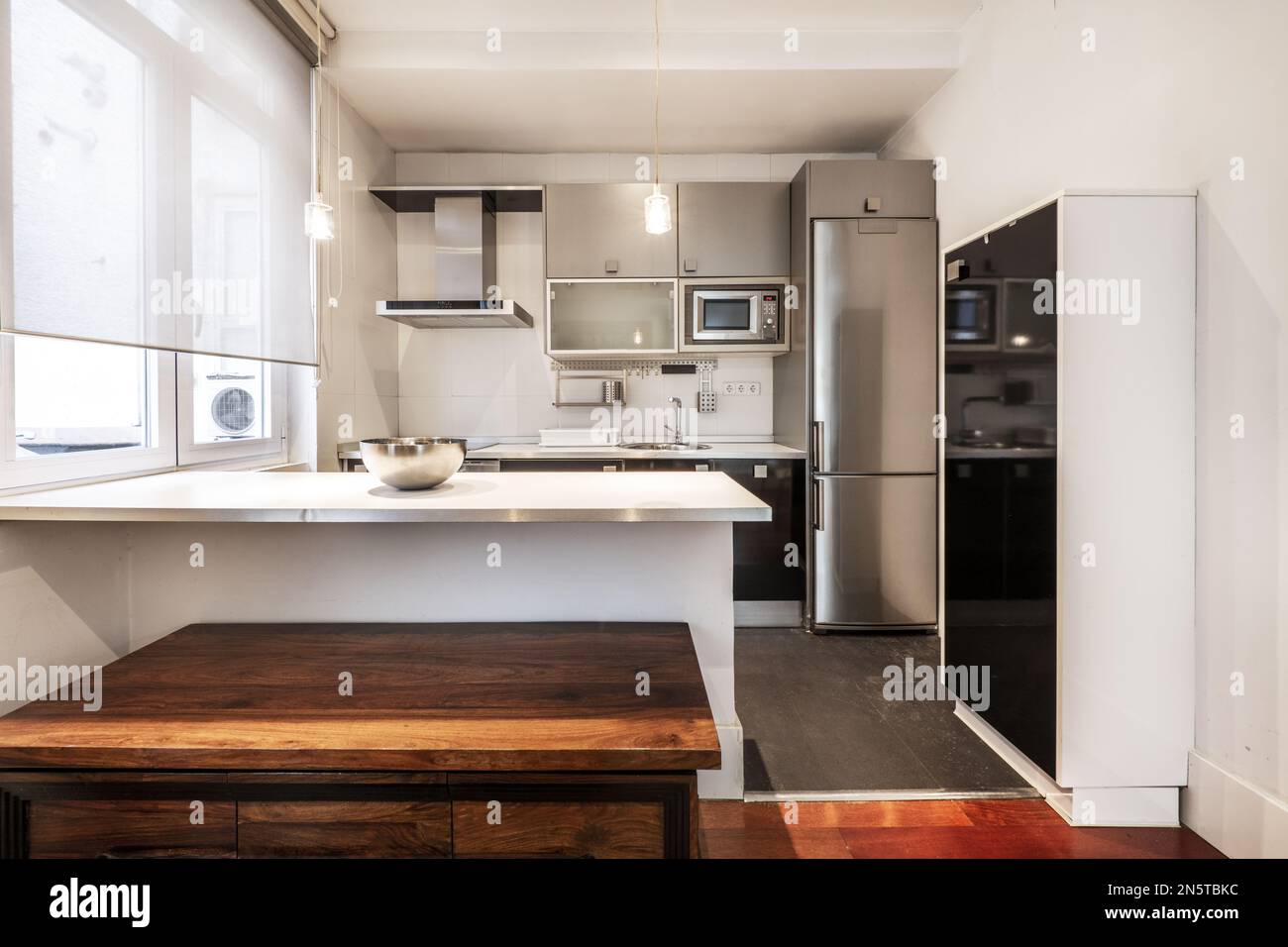 Open kitchen furnished with base units in gloss black, white countertop ...