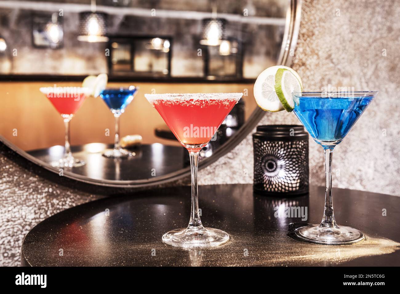 Some red and blue cocktails with sugar and salt on a black table next ...