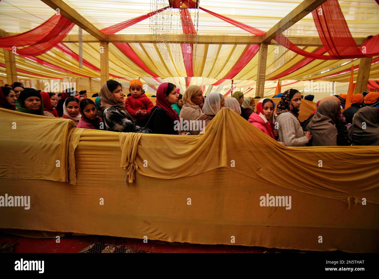 Sikh devotees stand in a queue to offer prayers at a gurudwara, or Sikh ...