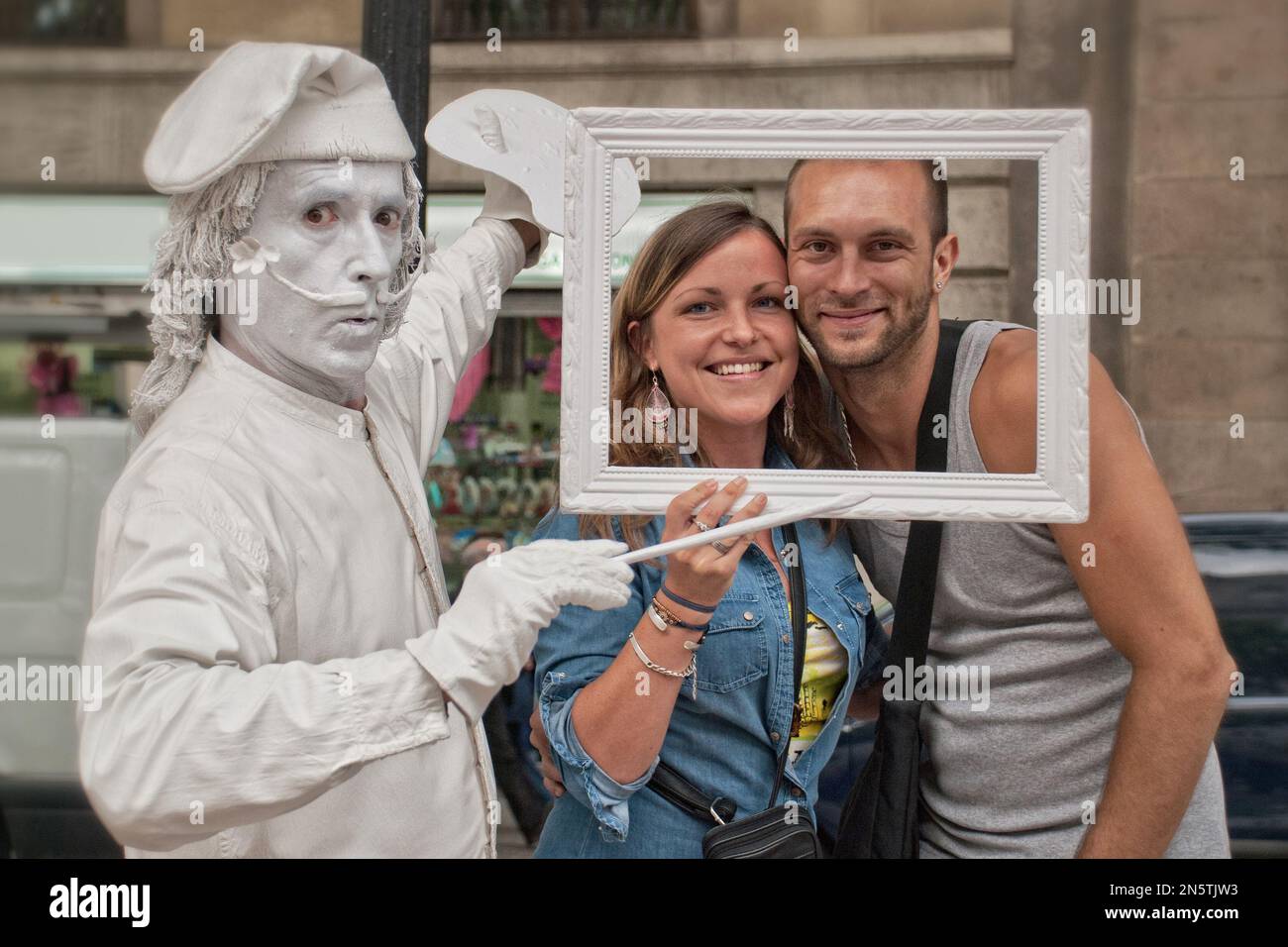 An all white mime artist in Barcelona holding frame around a young ...