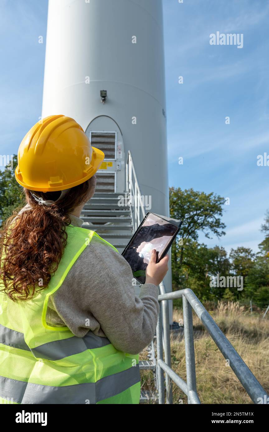 Female engineer with yellow helmet is holding a digital tablet while ...