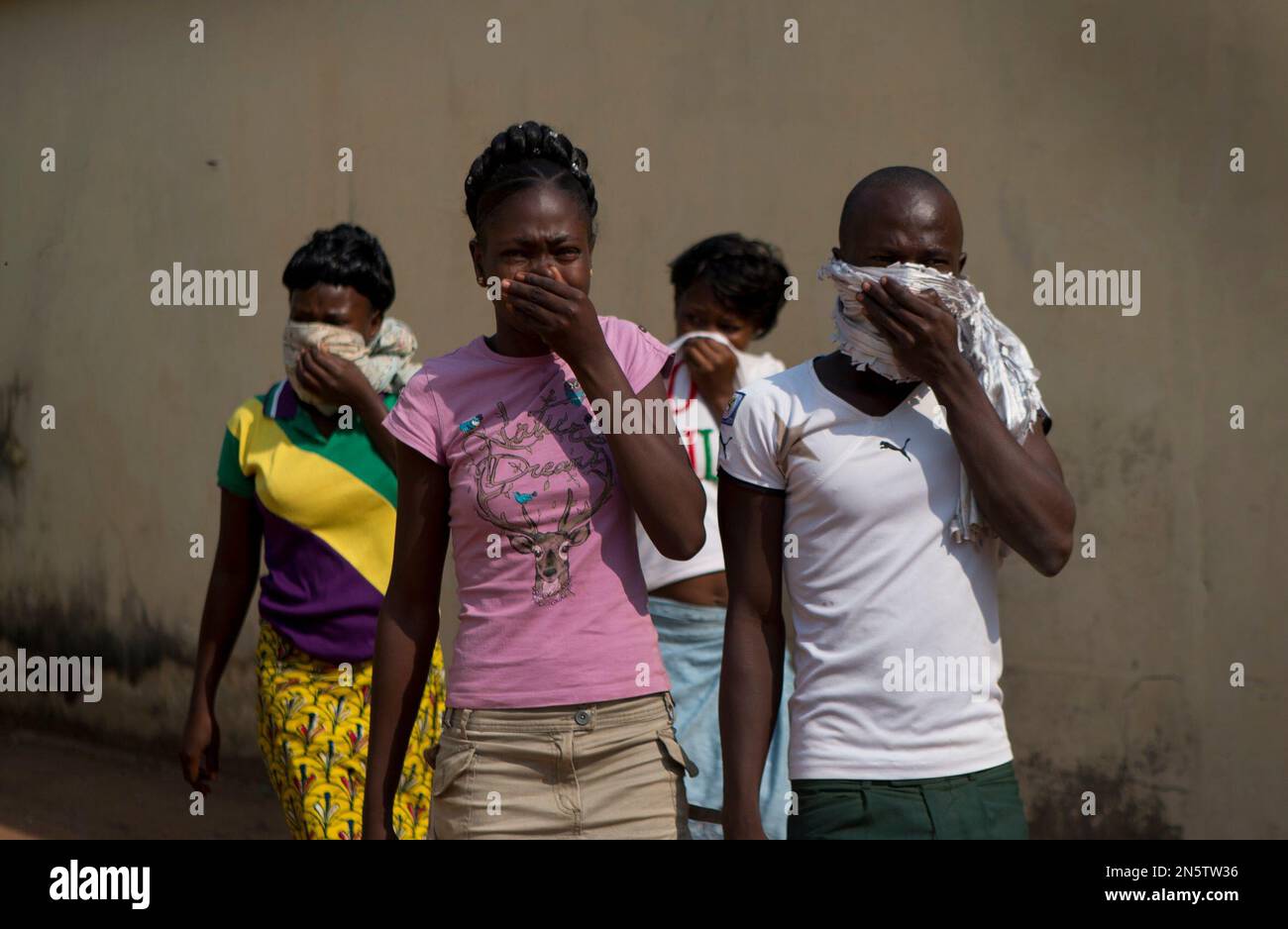 Family members cover their mouths and noses against the smell as they ...