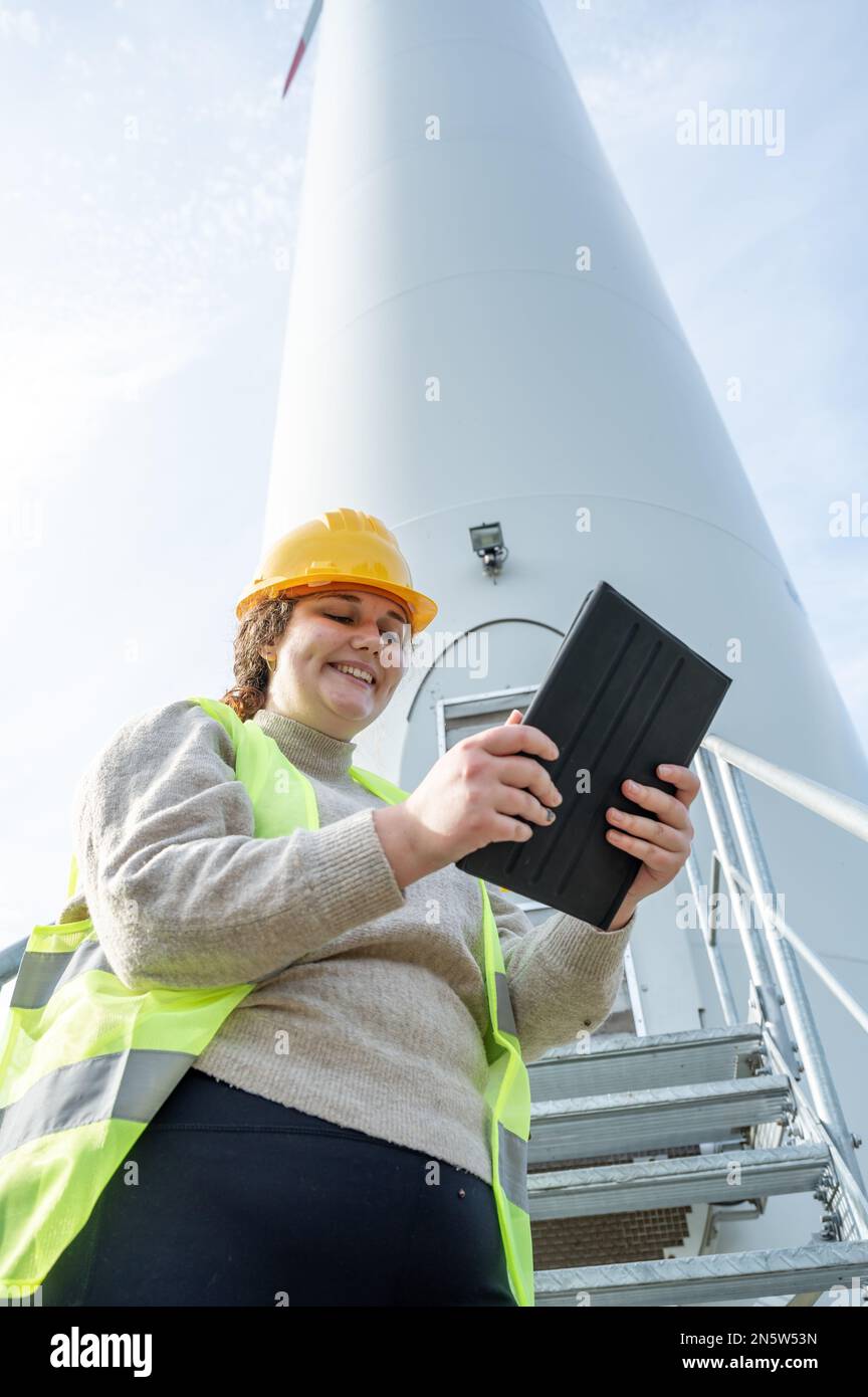 Female engineer with brown curly hair and yellow hat is laughing while ...