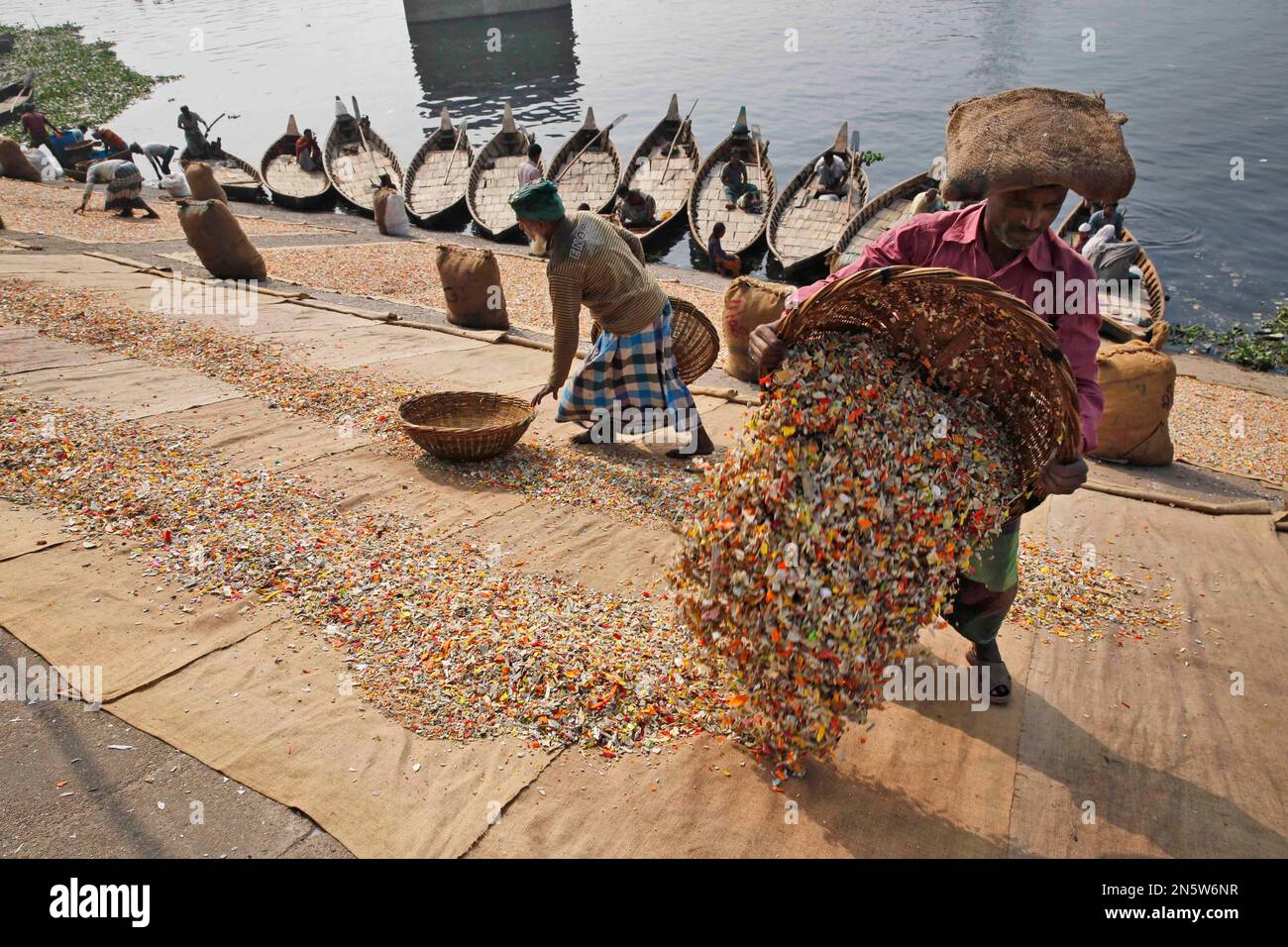 Bangladeshi vendors dry recycled plastic on an embankment in Dhaka ...
