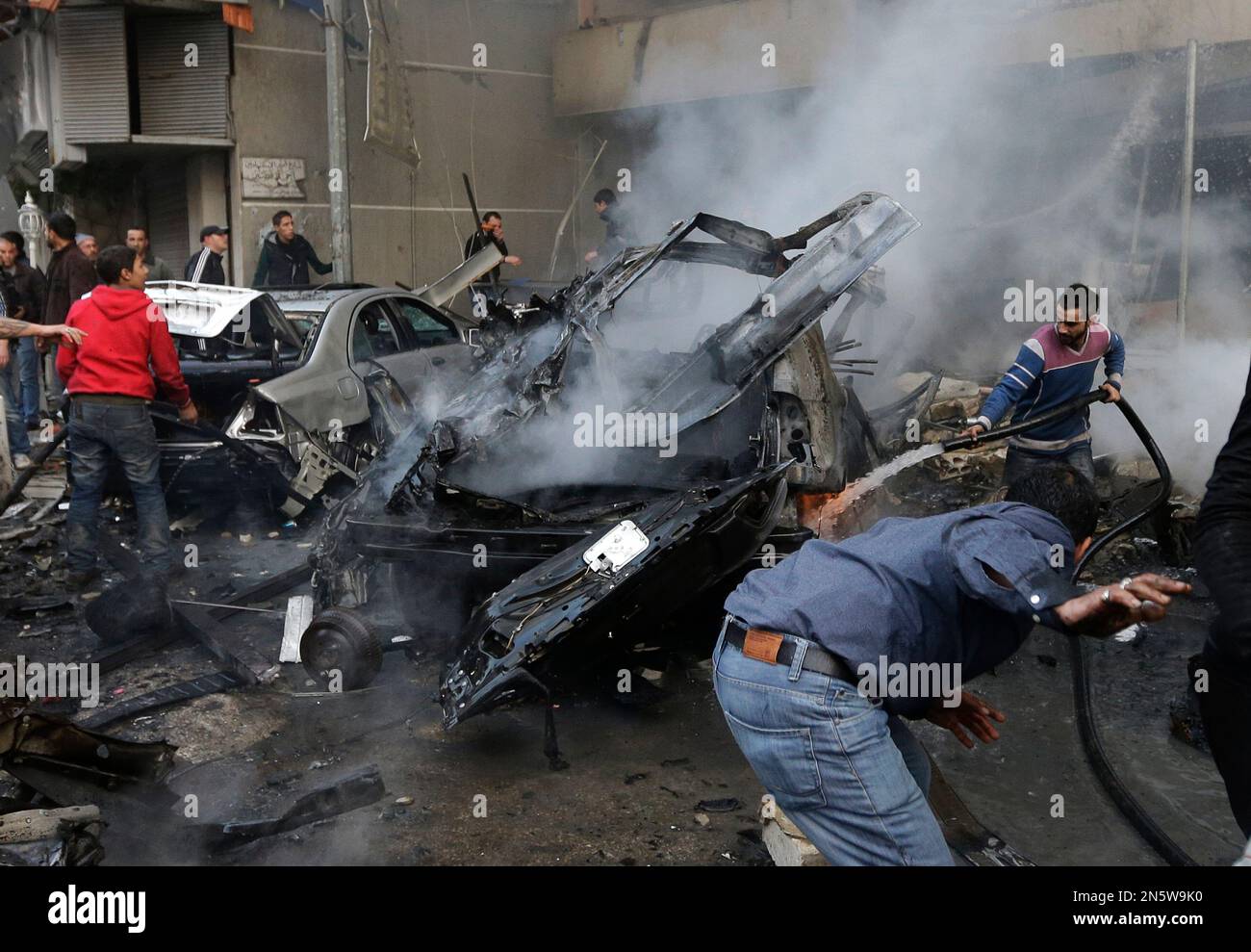 Lebanese men extinguish burned cars at the site of an explosion in a ...