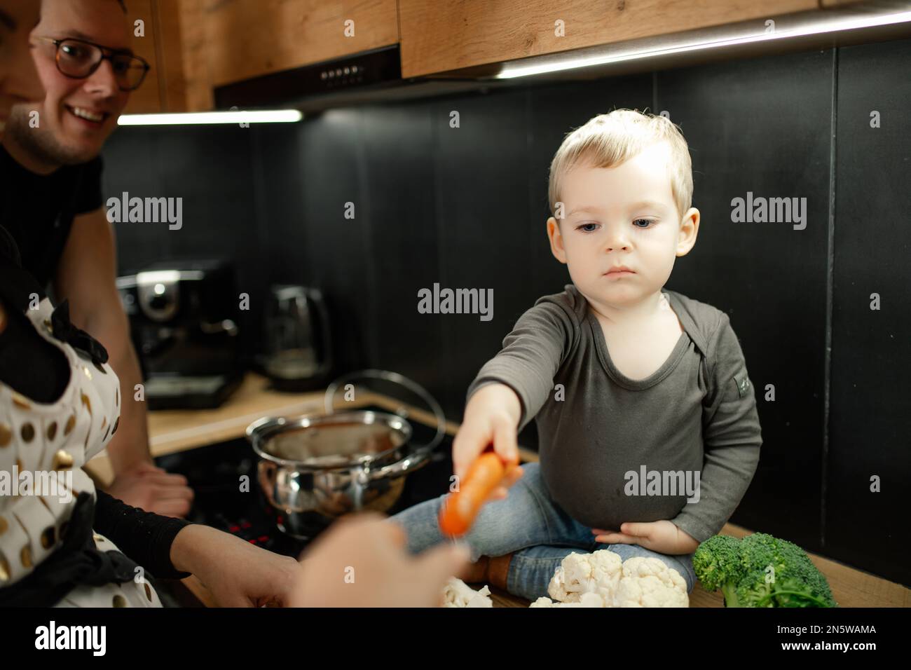 Close up little blond boy giving carrot to cropped parents hand ...