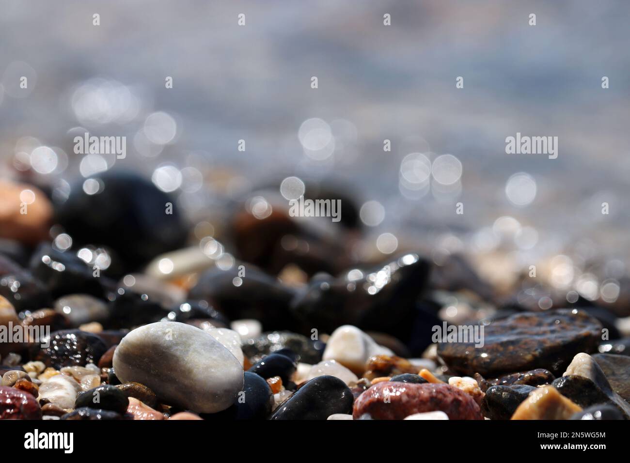 Wet pebble stones on blurred background of sea waves. Beach vacation ...