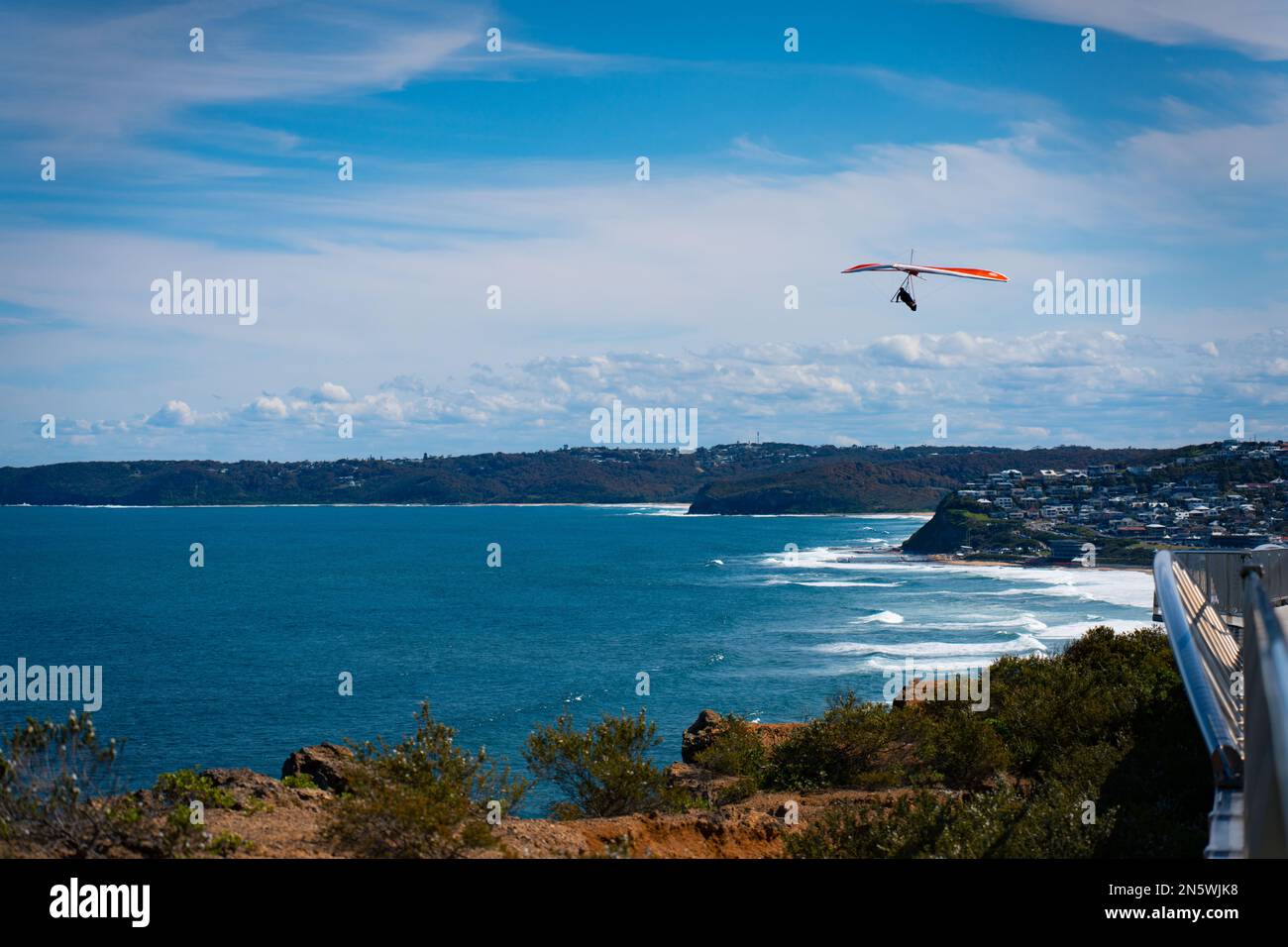 A hang glider soaring over a tranquil azure sea on a clear, sunny ...