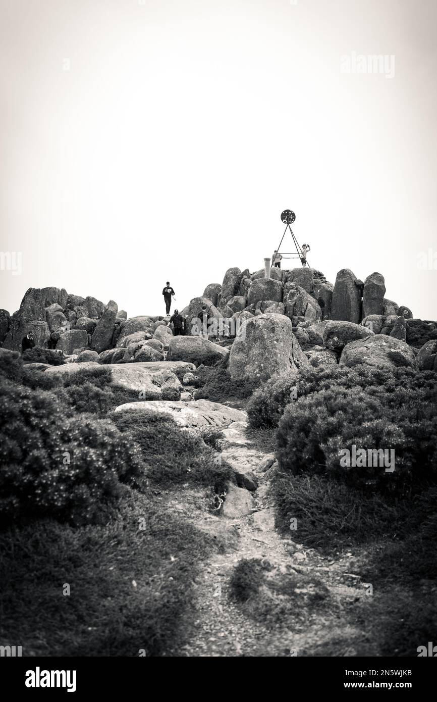 A group of people stand atop a scenic rock formation, taking pictures ...