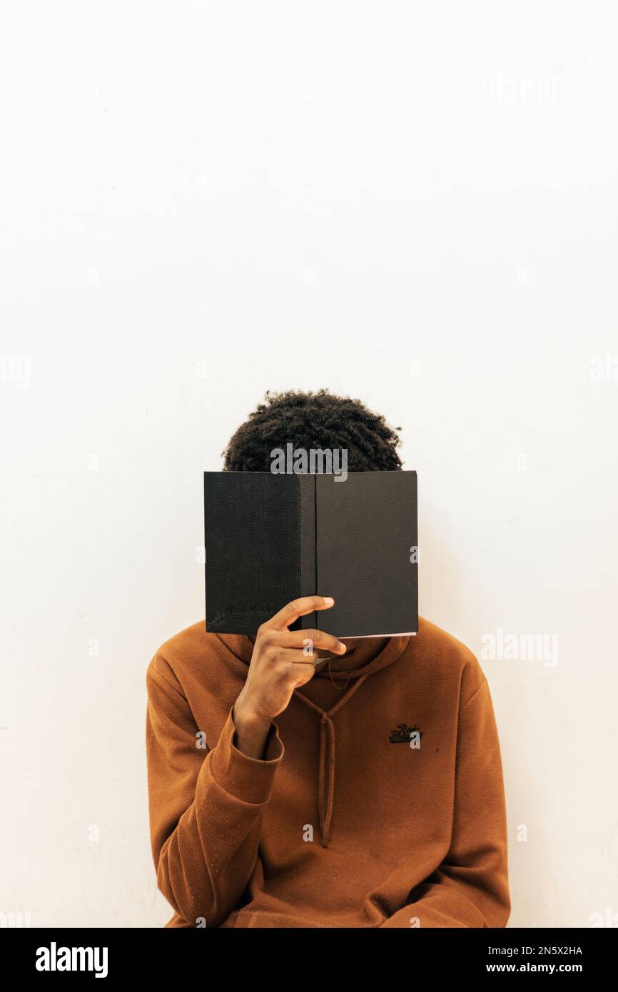 Man covering his face with a book. White background Stock Photo - Alamy