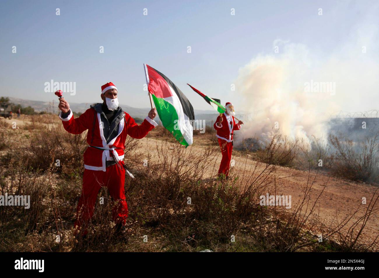 Palestinian protesters wearing Santa Claus costumes wave Palestinian ...
