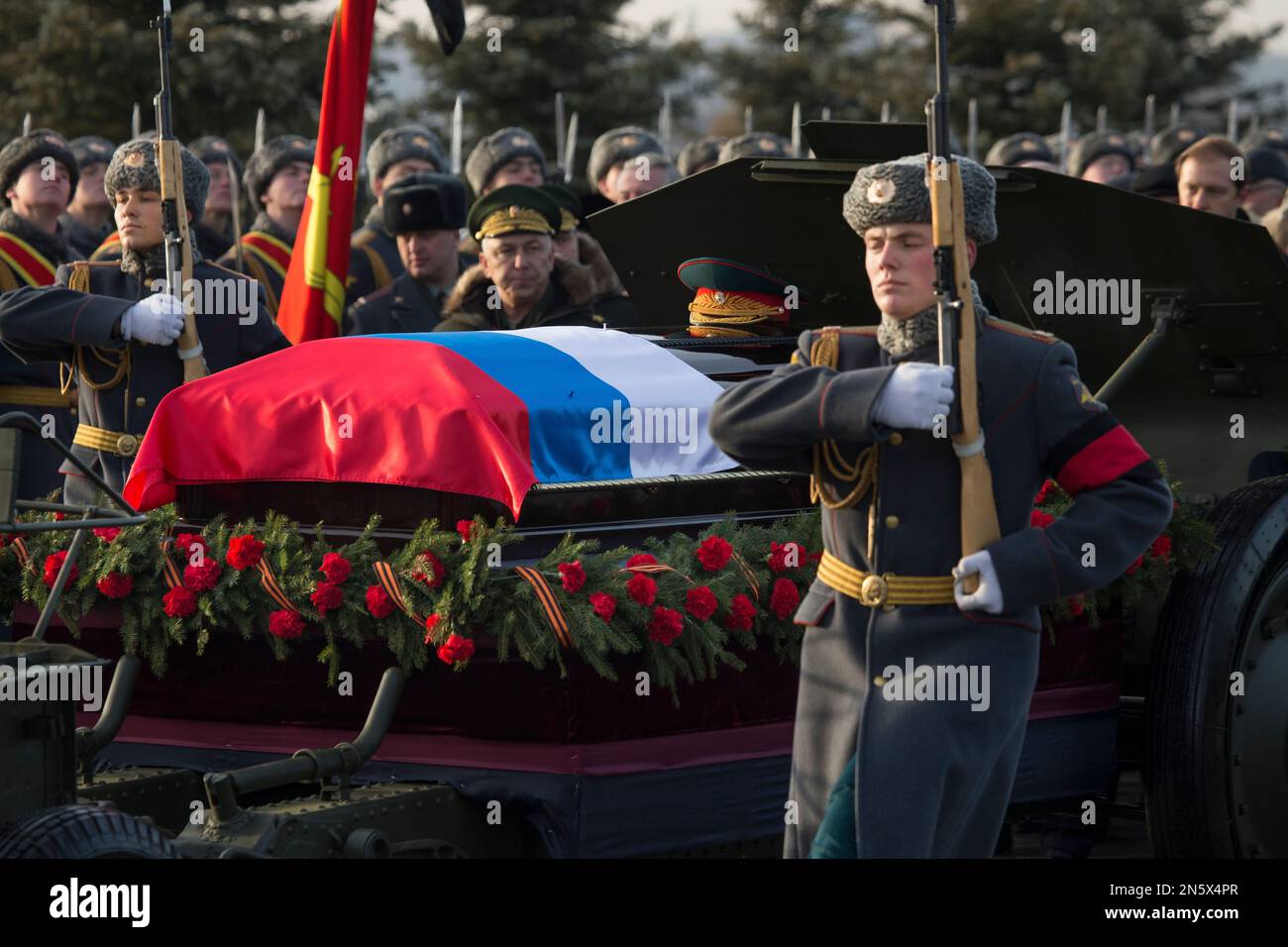Honor guards walk alongside an armored personnel carrier pulling the ...
