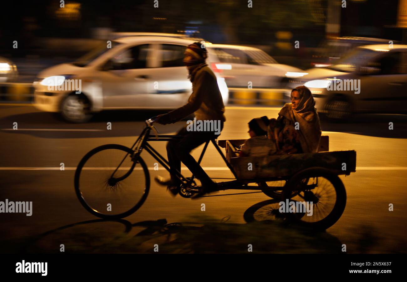 An Indian family rides a cycle rickshaw on a winter night in New Delhi ...