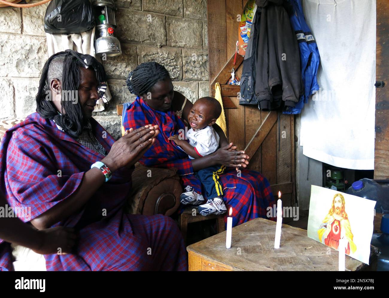 A Kenyan Christian Masai with his wife and child offer prayers in front ...