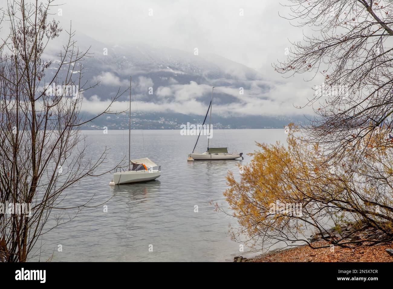 2 covered sailboats in the water and fog on the lake. Snow-covered ...