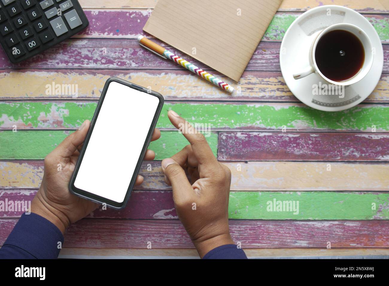 Top view of man hand holding smart phone with empty screen on office ...