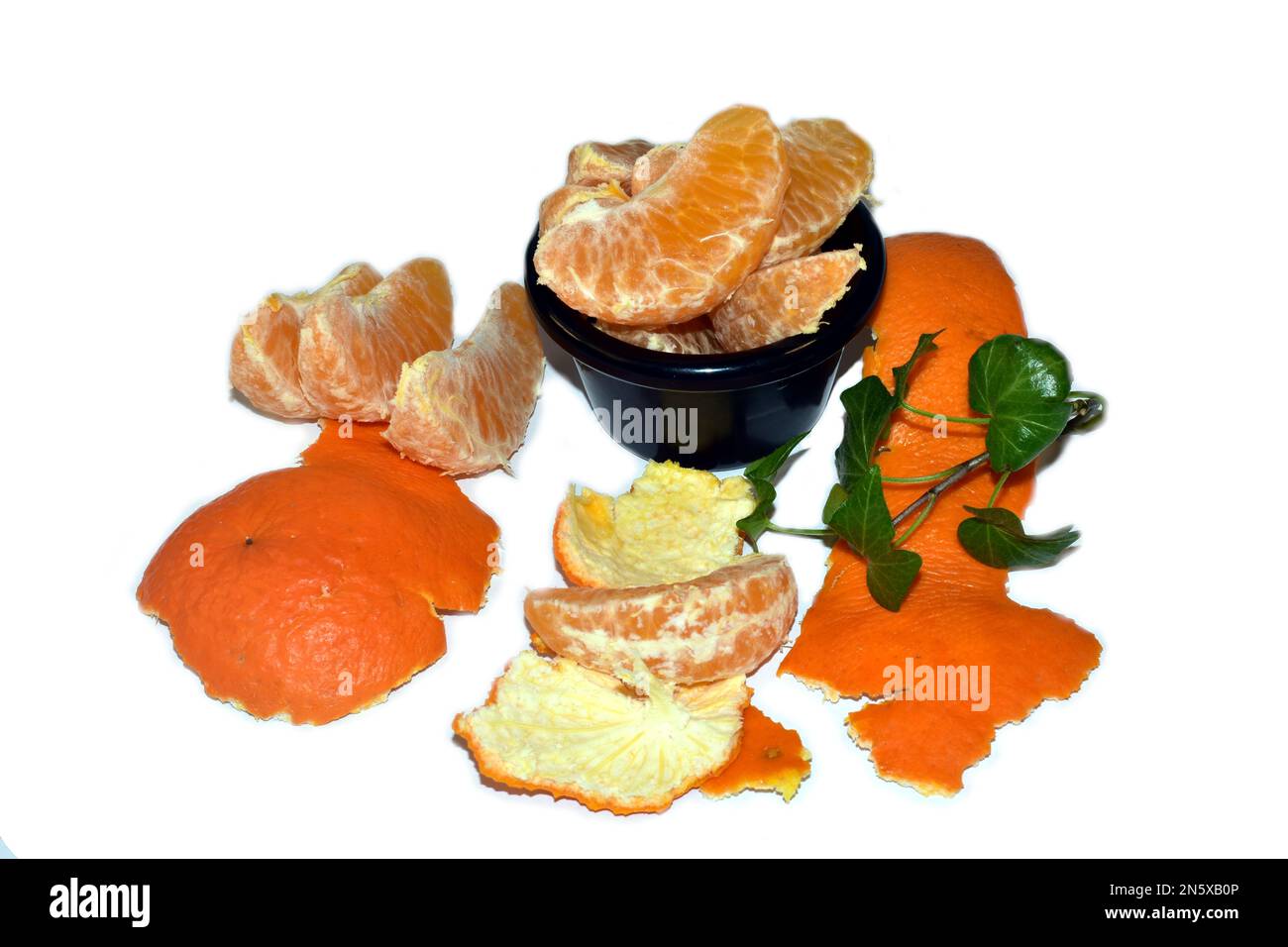 Peeled tangerine in a black bowl with peel on the side isolated on a ...