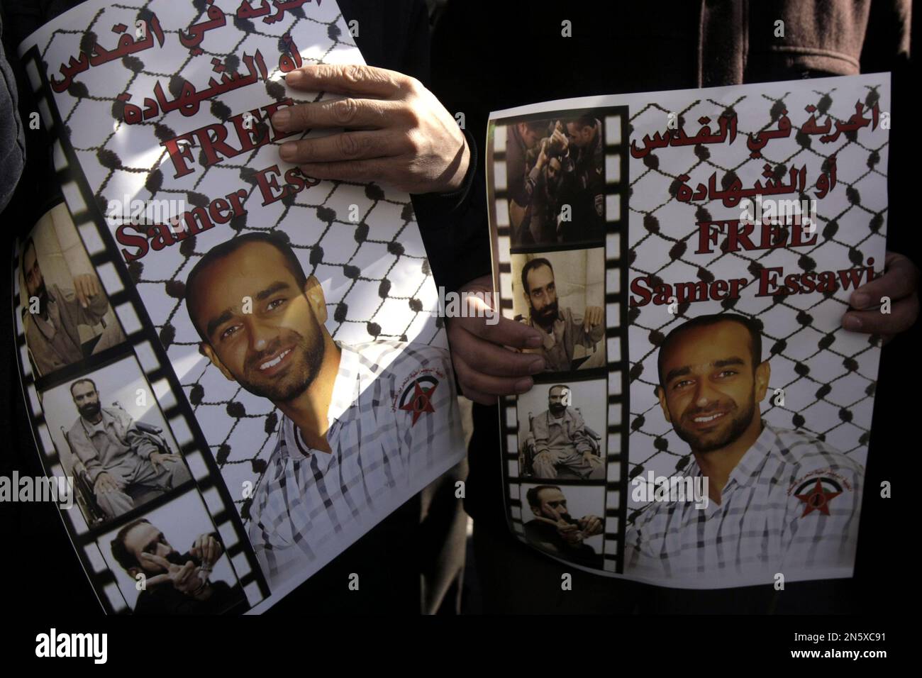 Palestinians hold posters showing Palestinian prisoner Samer Issawi ...