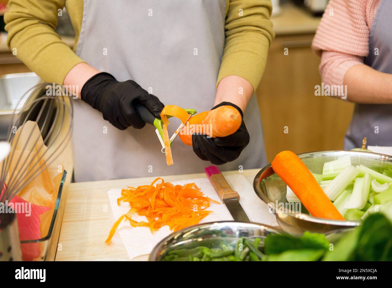 women's hands hold a vegetable peeler and peel carrots, the process of ...