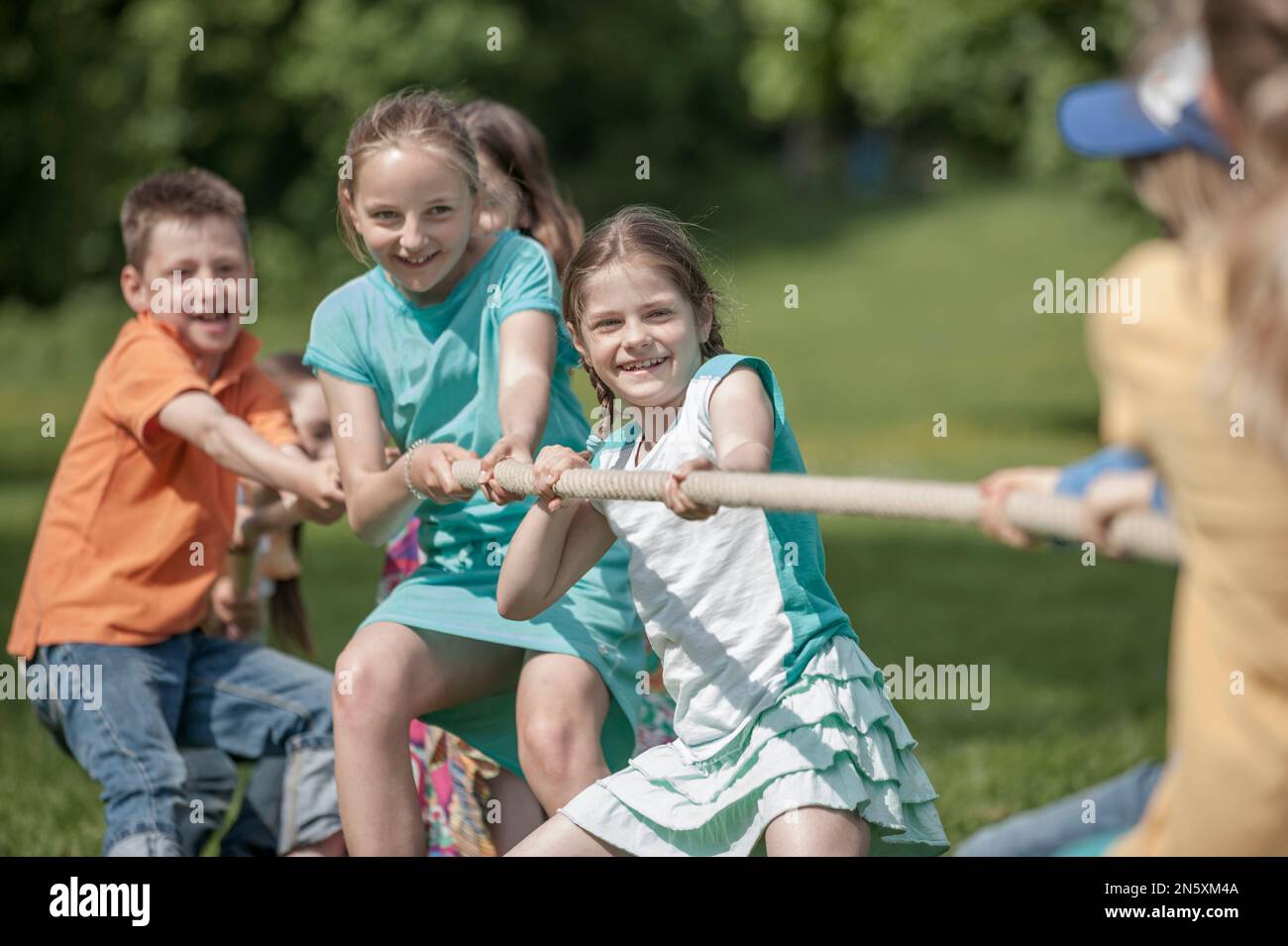 Group of children playing tug-of-war in a park, Munich, Bavaria ...