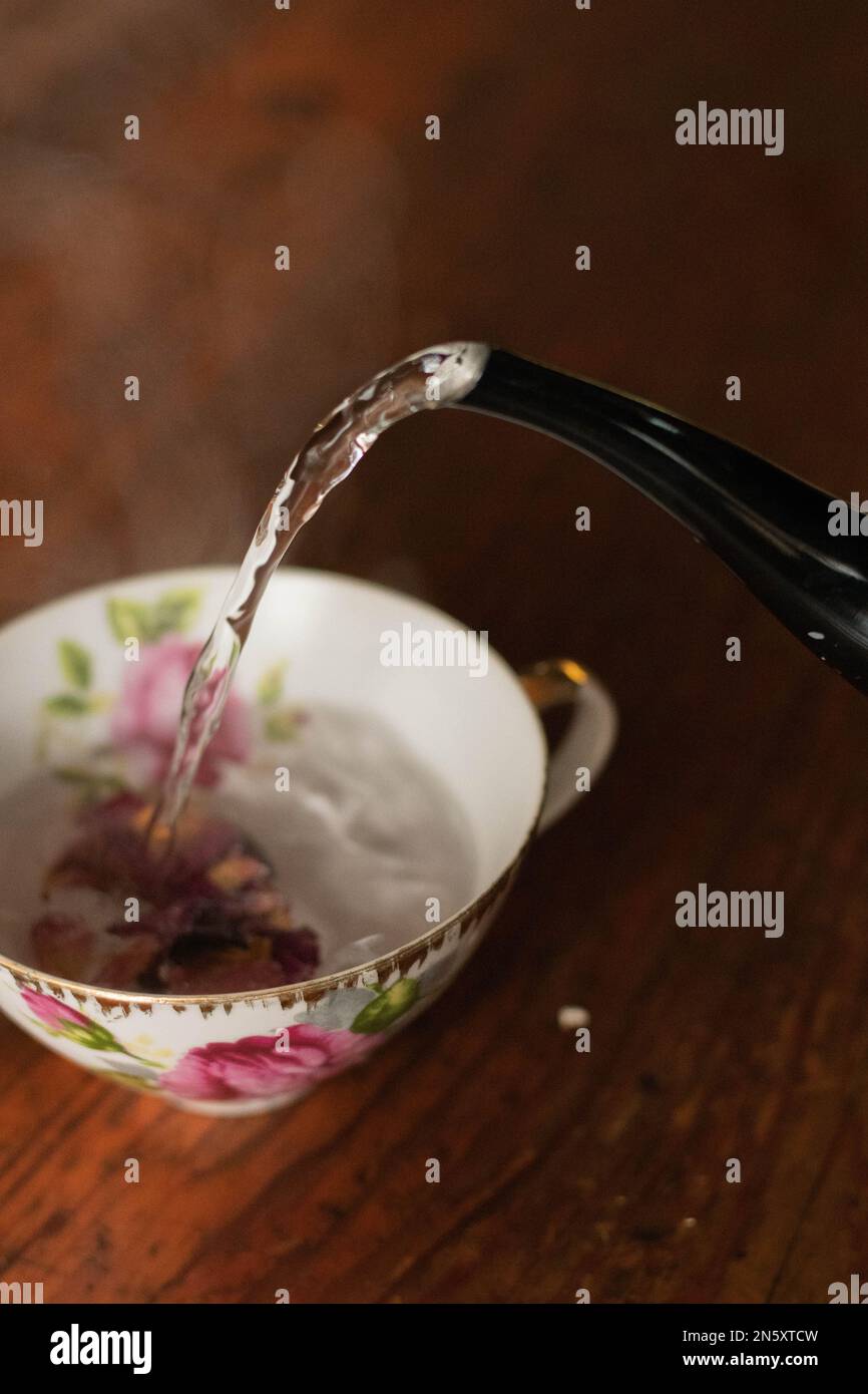 black kettle tipping boiled water into tea cup Stock Photo - Alamy