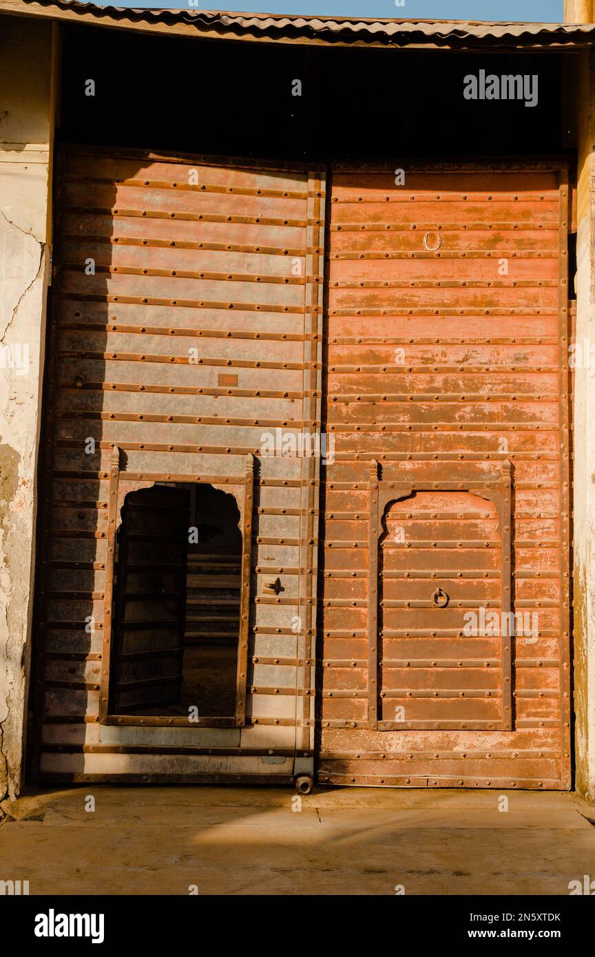 A vertical shot of an old gate with two knockers, in Mandawa haveli ...