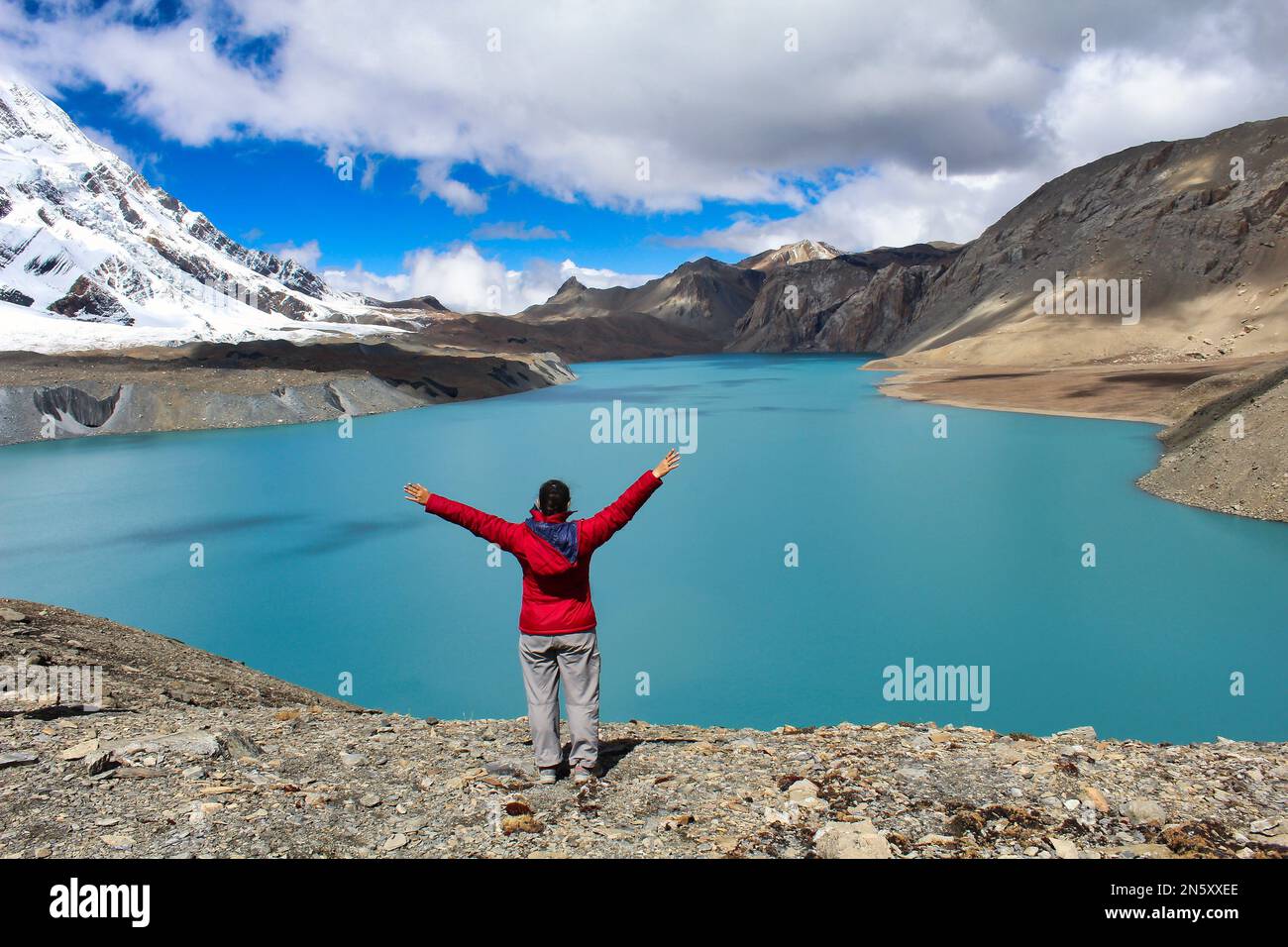 A trekker enjoys the view of the magnificient luminescent blue Tilicho ...