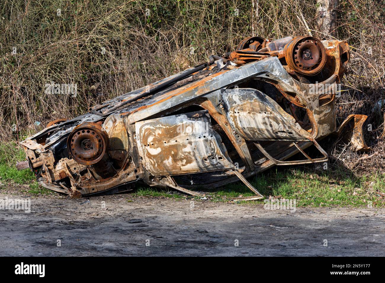 Wrecked car turned upside down on the side of the road after being burned in a crash accident ...