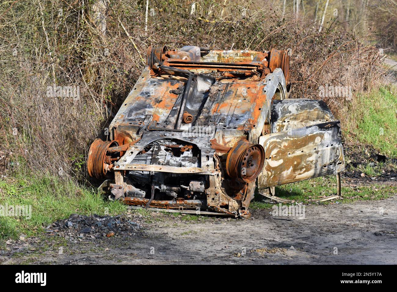 Wrecked car turned upside down on the side of the road after being burned in a crash accident ...